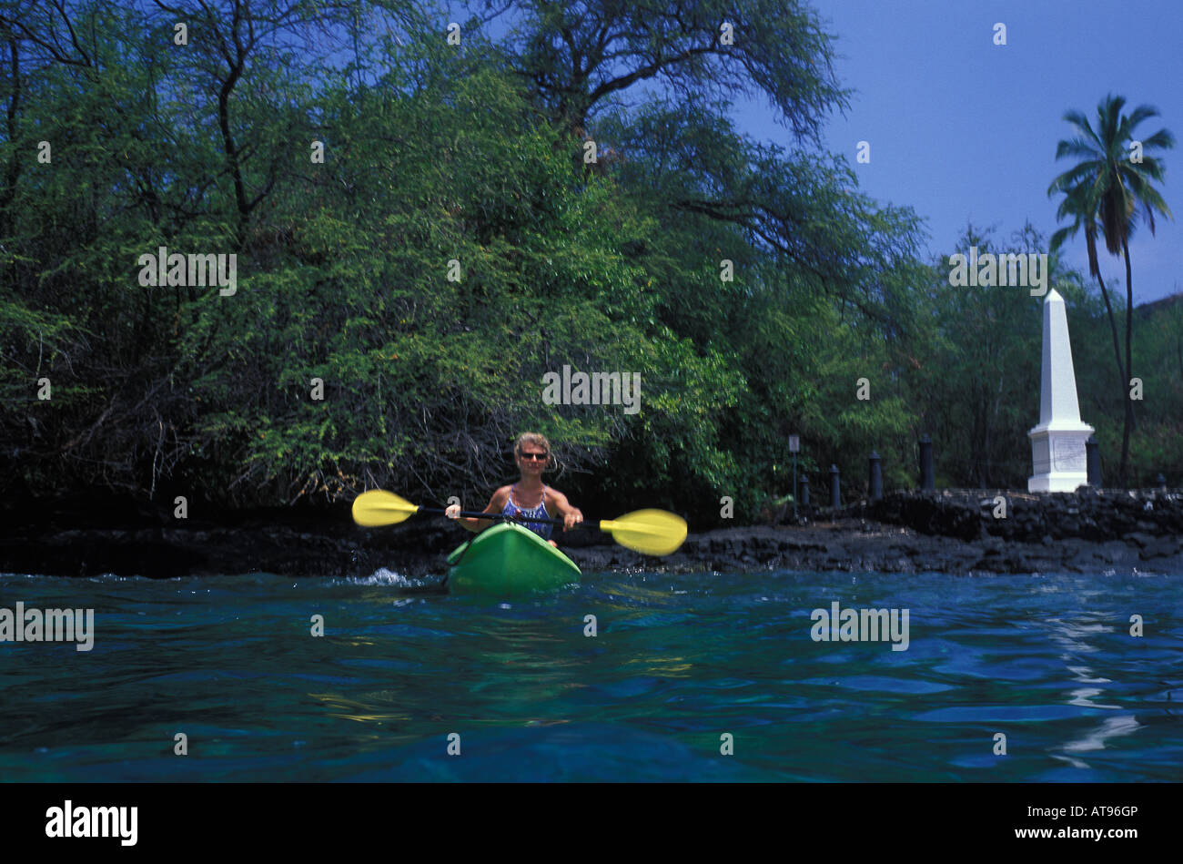 Woman kayaking in Kealakekua bay with Captain Cook monument in rear ...