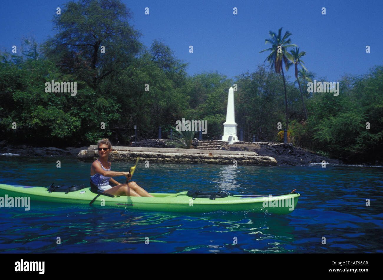 Woman kayaking in Kealakekua bay with Captain Cook monument in rear ...