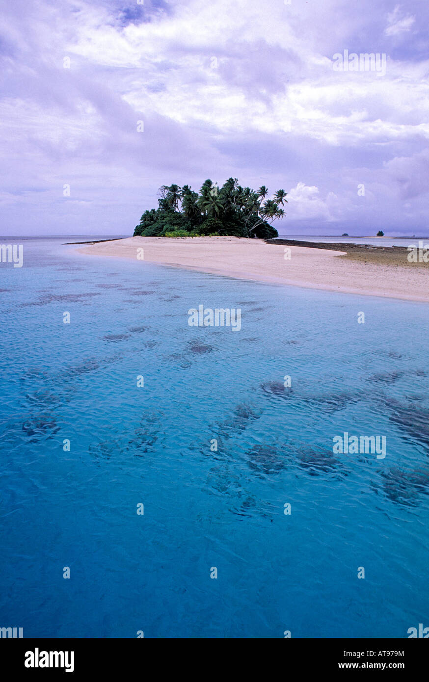 The calm, clear blue Pacific ocean surrounds the white sand crescent of ...