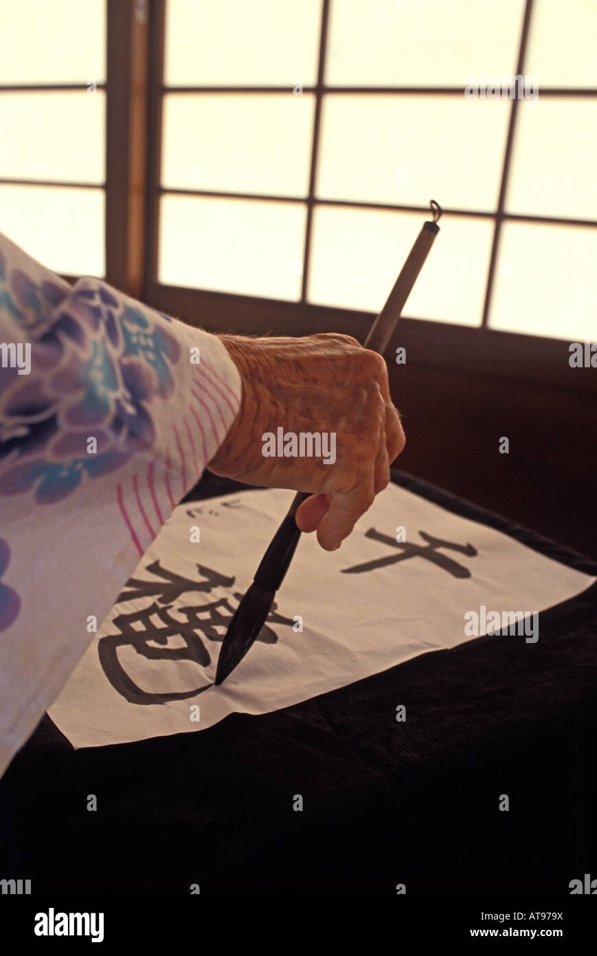 Close-up of a kimono draped arm with hand engaged in calligraphy of ...