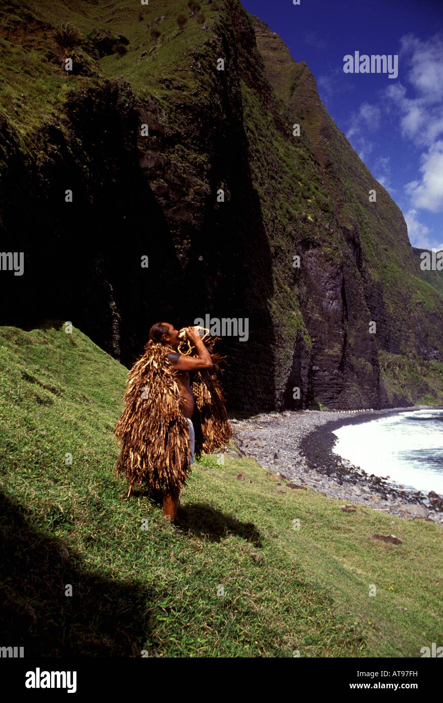 Man wearing traditional Hawaiian raincoat blowing conch shell at the ...