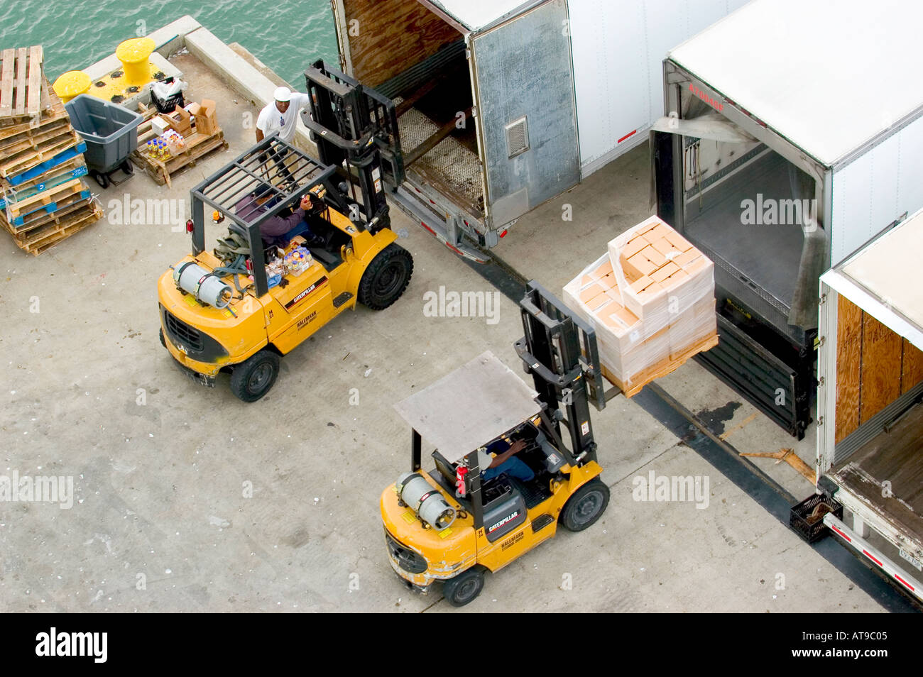 2 Fork lift vehicles unload supplies from semi truck trailers Stock ...