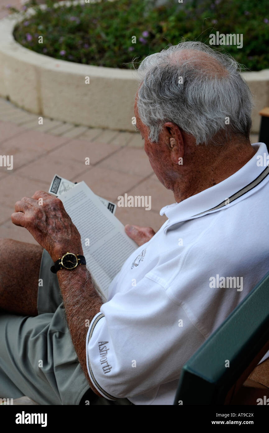 Adulty senior male wearing hearing aid reading book Stock Photo - Alamy