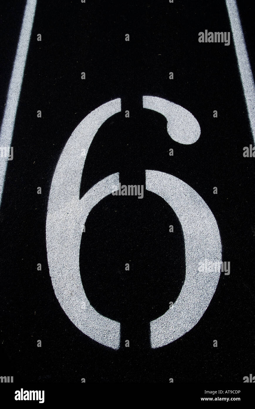 White number six on the black surface of an athletic running track ...