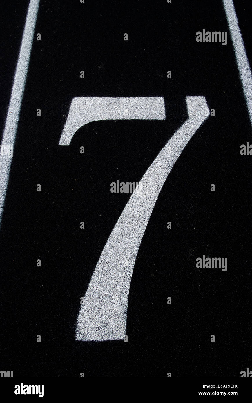 White number seven on the black surface of an athletic running track ...