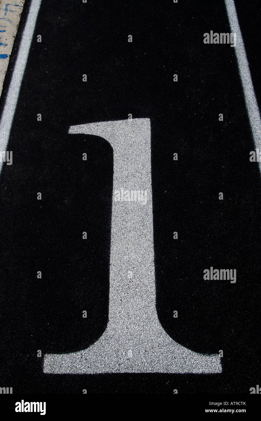 White number one on the black surface of an athletic running track ...