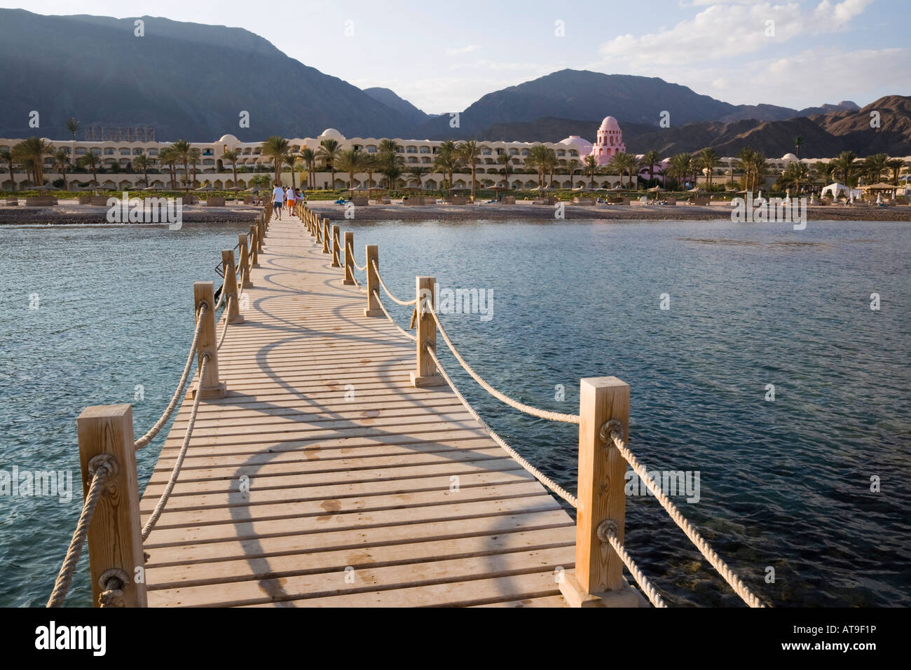 Wooden jetty in Red Sea with view back to beach and luxury hotel resort ...