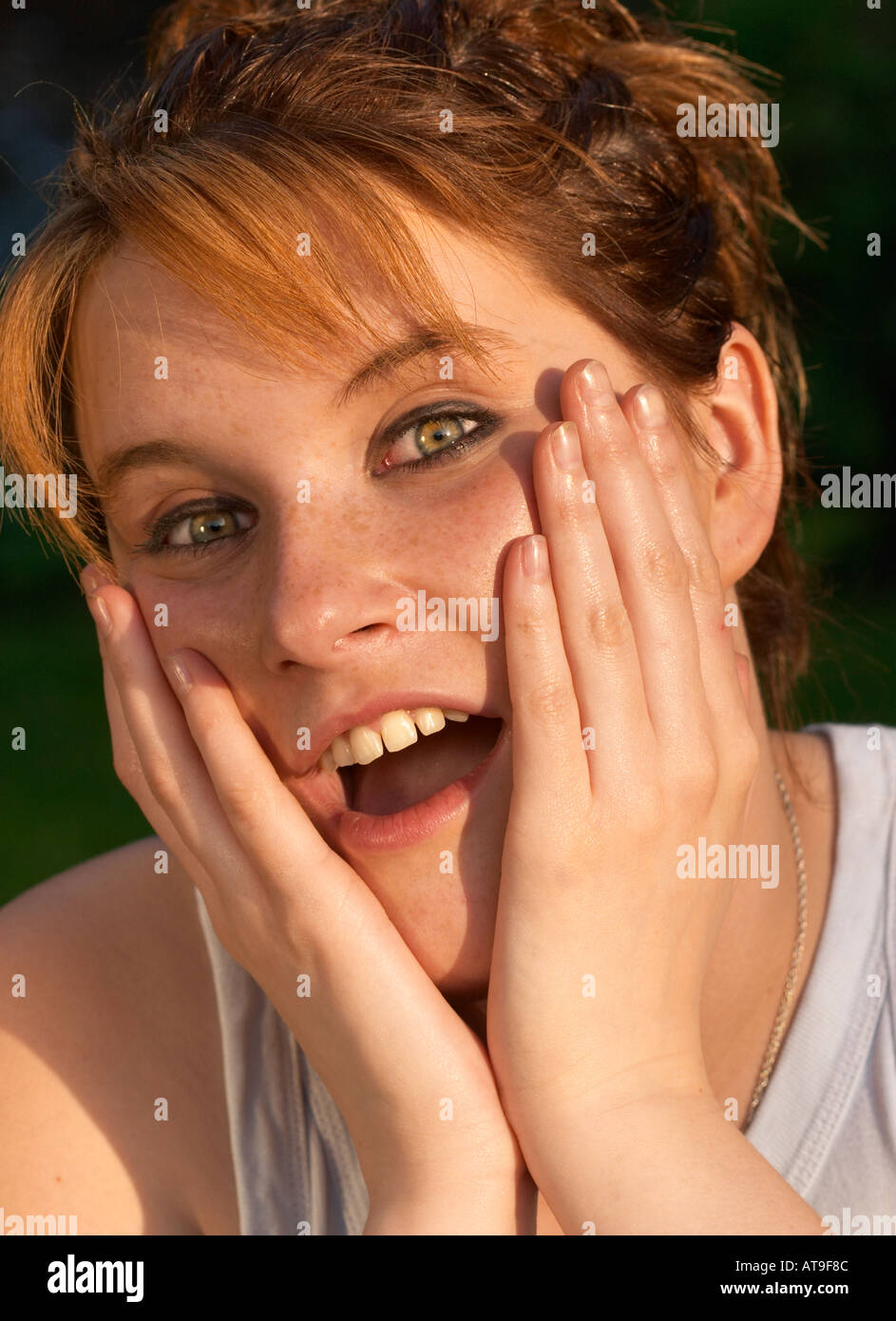 Young woman cupping face in hands surprised Stock Photo - Alamy