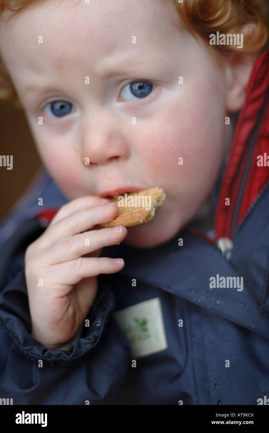 A young boy eating a biscuit outdoors Stock Photo - Alamy