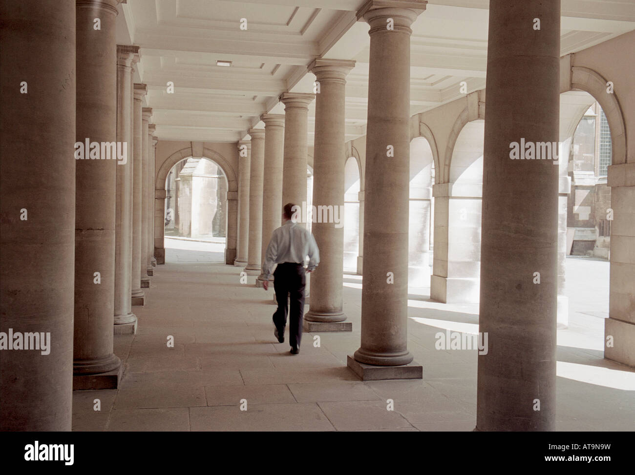 Man walking through line of columns Stock Photo - Alamy
