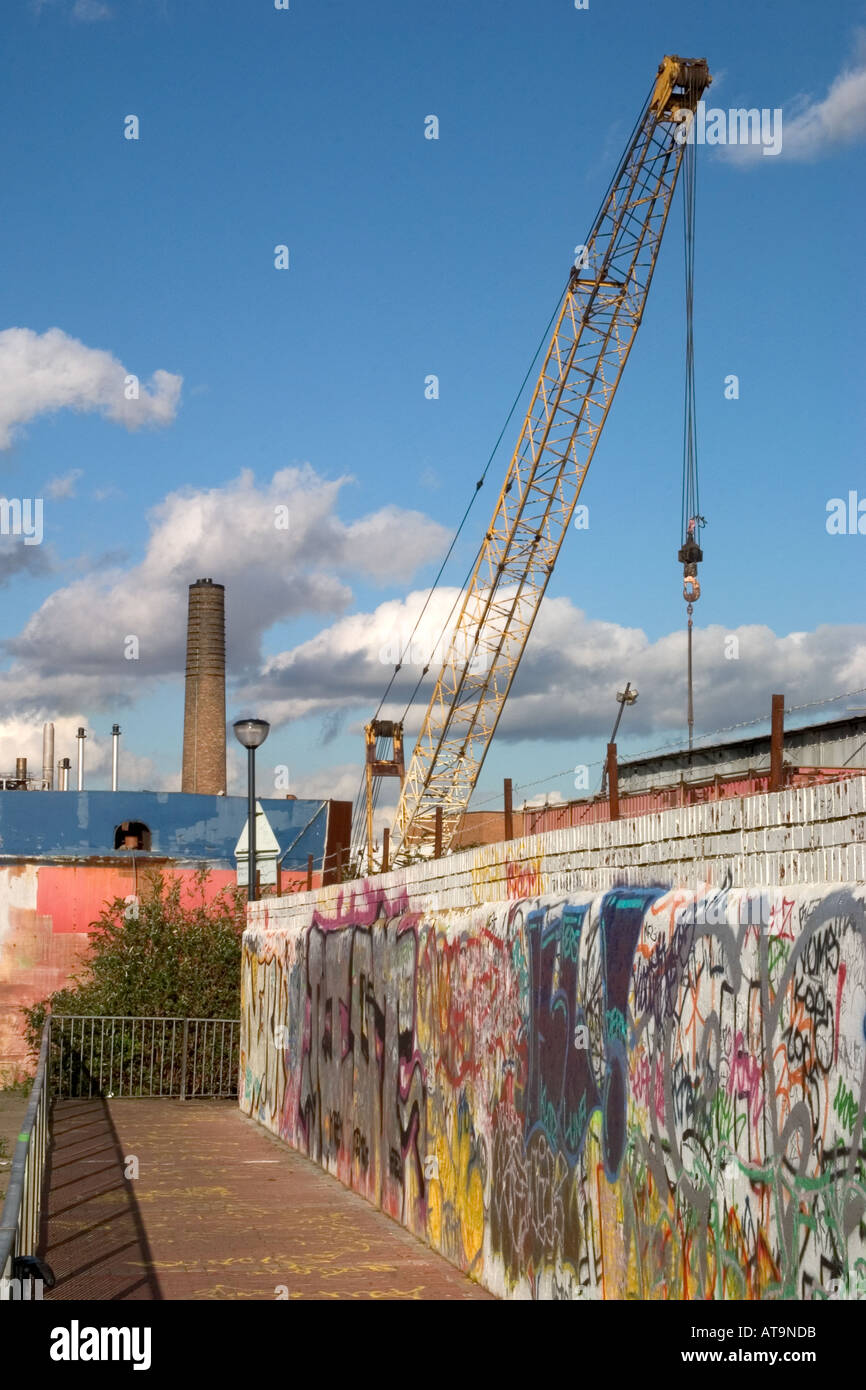 Industrial waterfront with colourful graffiti barbed wire and crane ...