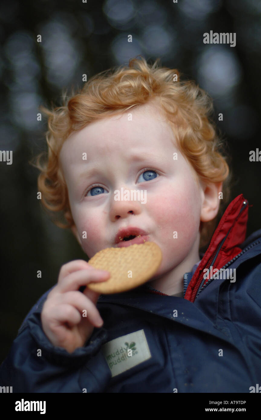 A young boy eating a biscuit outdoors Stock Photo - Alamy