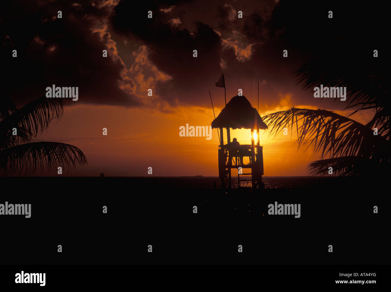 Sunset silhouette of lifeguard in raised hut on beach, Isla Mujeres ...