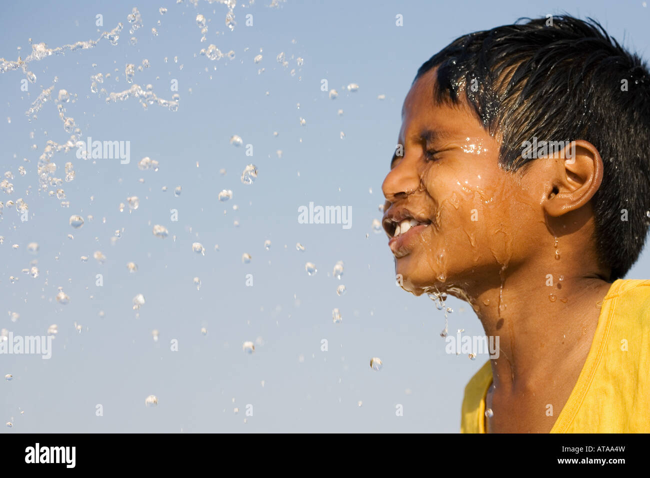 Indian boy splashing water on himself against a blue sky. India Stock ...