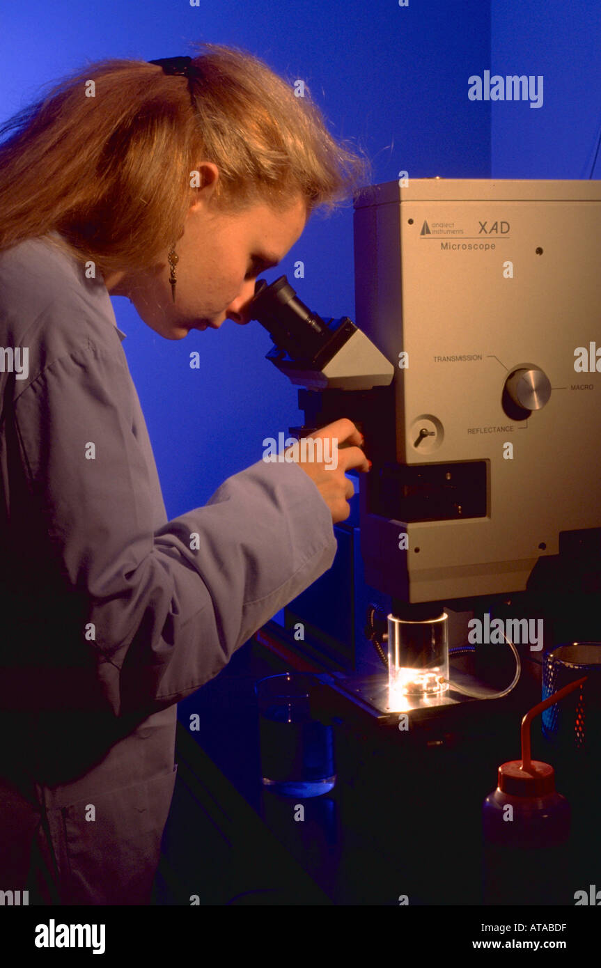 Research technician using microscope in product testing laboratory ...