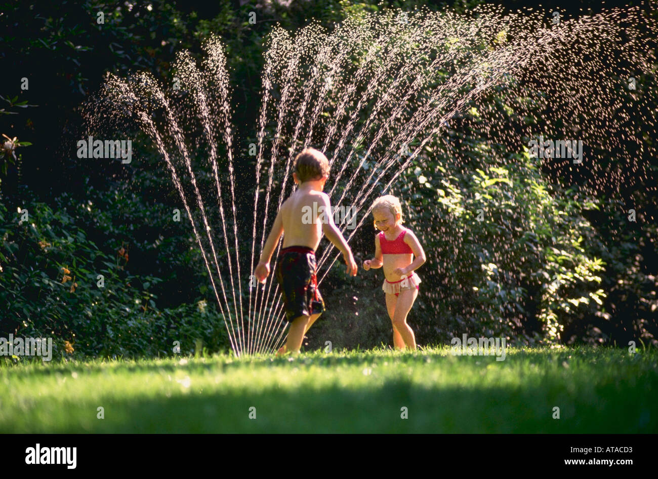 Kids running through sprinkler hi-res stock photography and images - Alamy