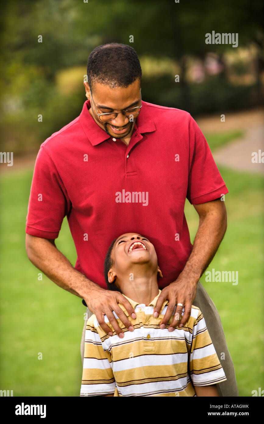Father standing behind son with hands on his shoulders as boy smiles ...