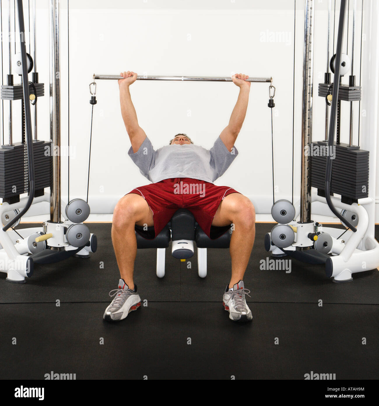 Man at gym lifting weights on weight machine Stock Photo - Alamy