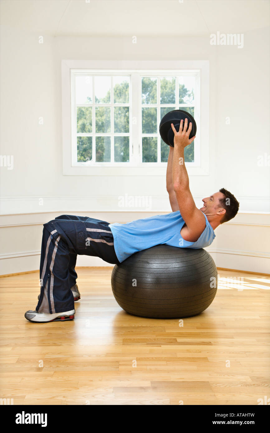 Man lifting medicine ball while on balance ball Stock Photo - Alamy