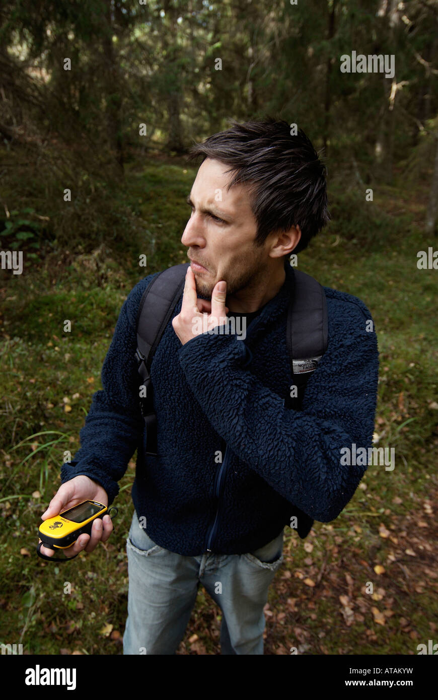 Young male hiker looking confused with an yellow GPS receiver in his ...