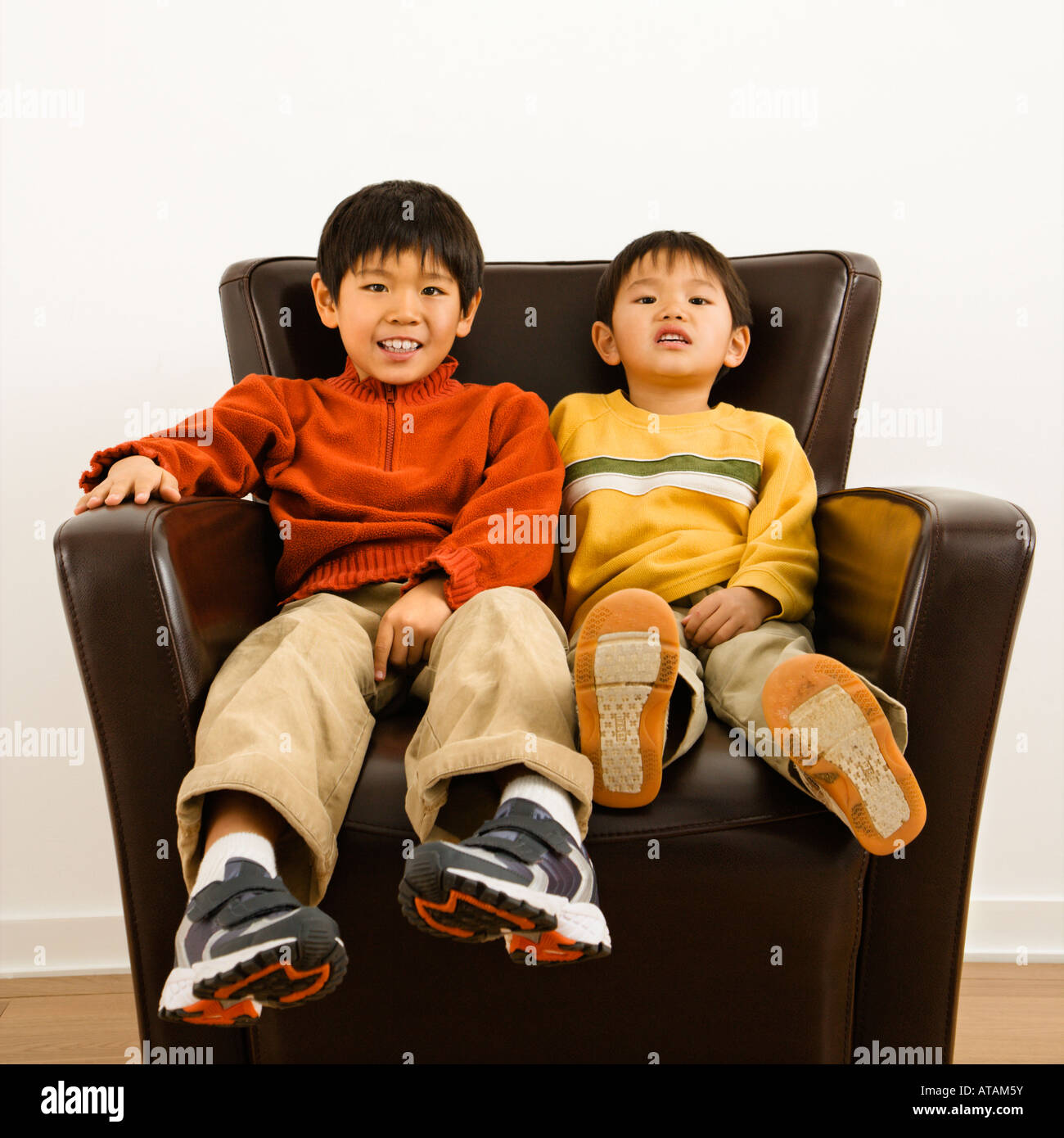 Two Asian brothers sitting in chair smiling Stock Photo - Alamy