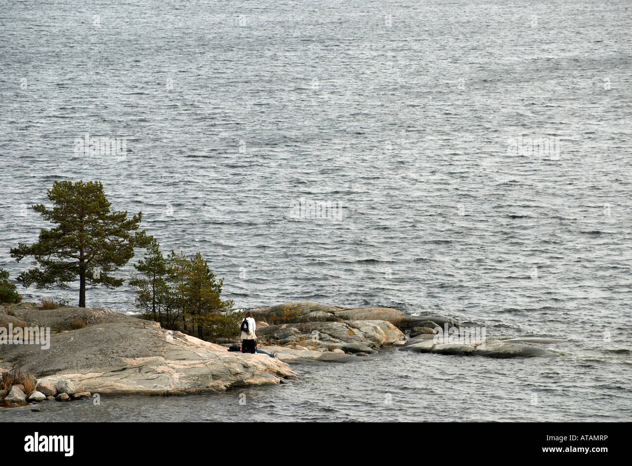 A woman on a small rocky peninsula at the Swedish coast Bjorno ...