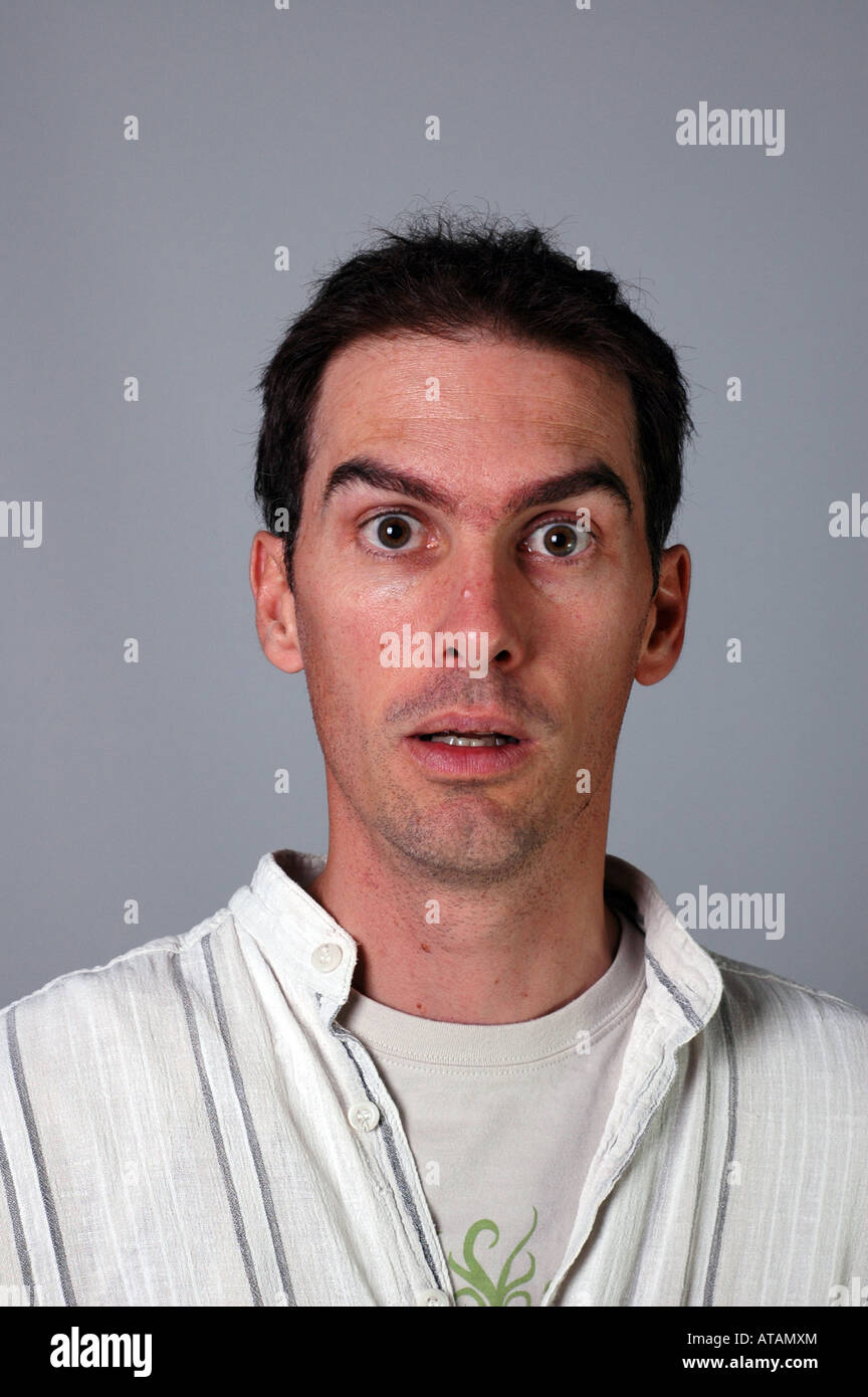 Young man slightly scruffy casually dressed with a shocked expression ...
