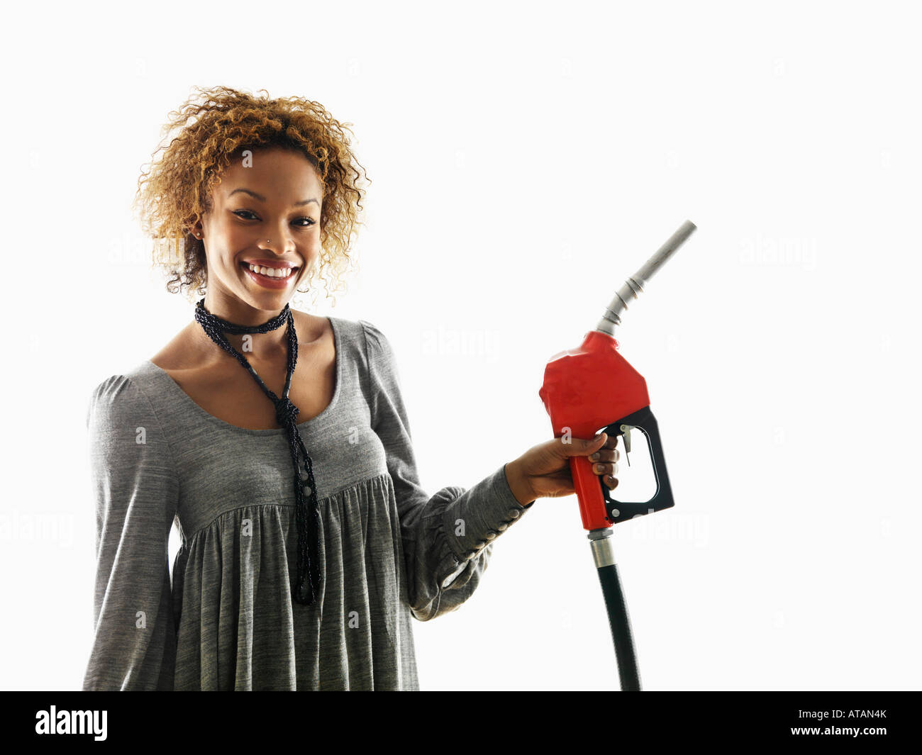 Portrait of pretty young woman smiling holding gas pump nozzle on white ...