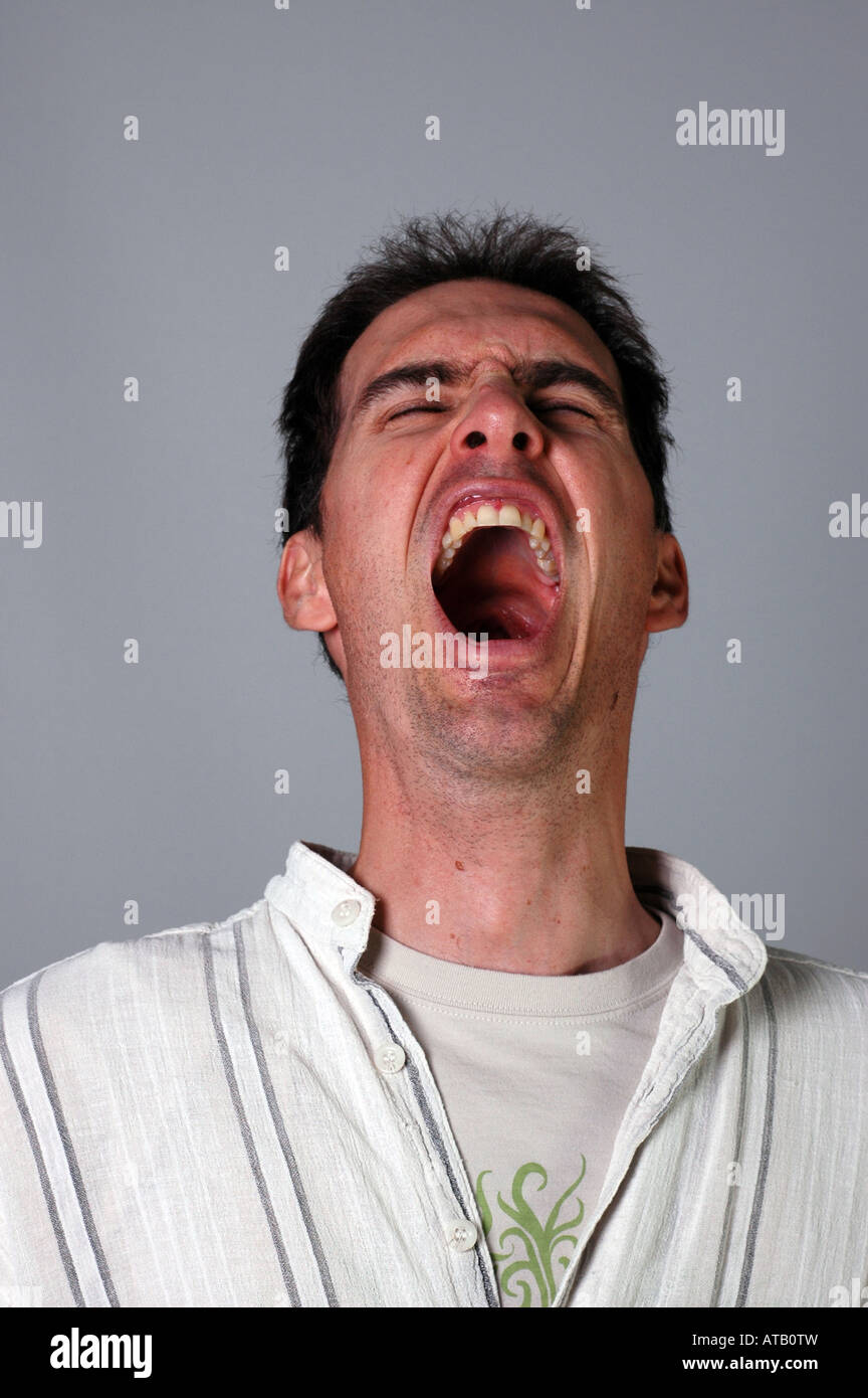 Casually dressed young man yawning with fatigue Or is he screaming and ...