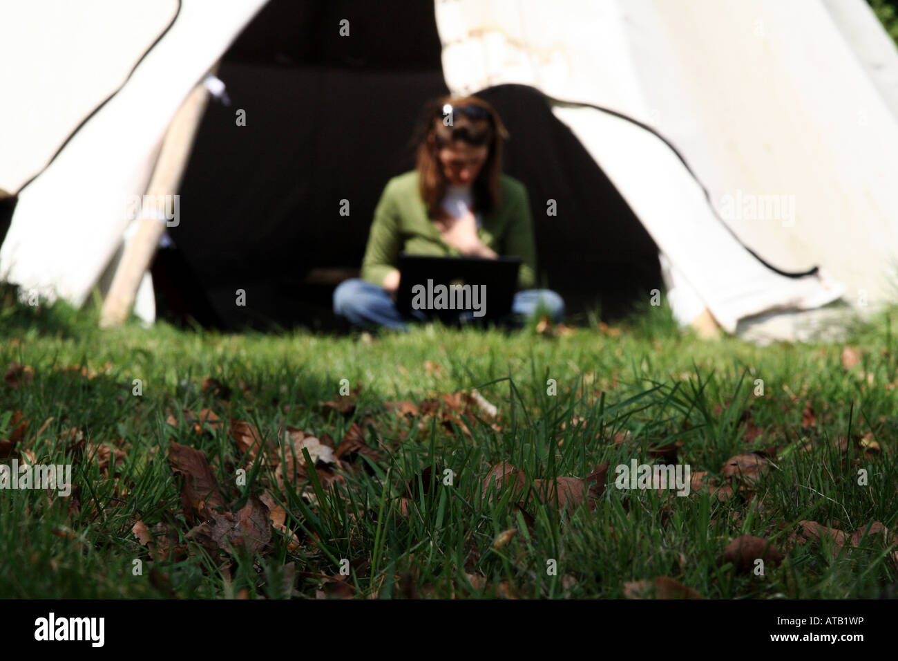 In tents: a young woman works on her laptop computer outside a tipi in ...
