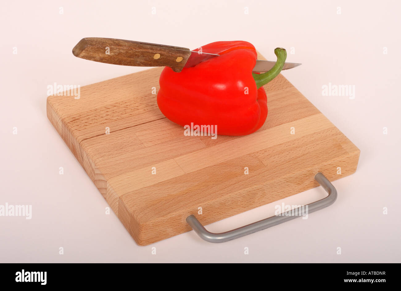 Red capsicum pepper on kitchen wooden chopping board with sharp knife ...
