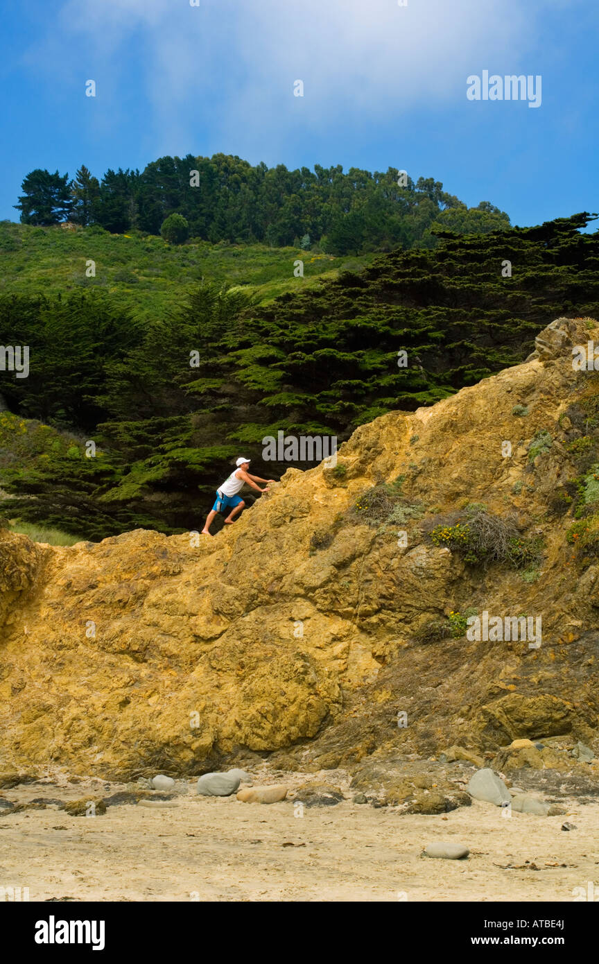 Man climbing on coastal cliffs at Pfeiffer Beach Big Sur Coast Monterey ...