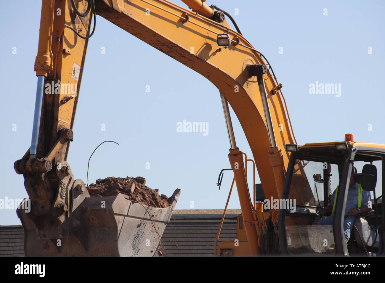 Bucketful being lifted by yellow mechanical digger Stock Photo - Alamy