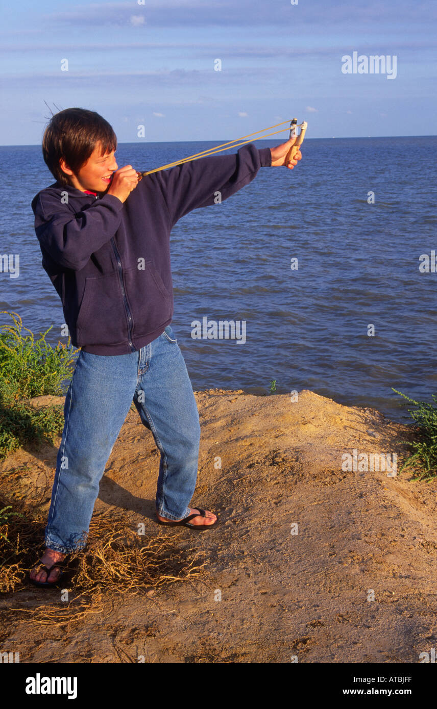 Boy firing his catapult into the sea Stock Photo - Alamy