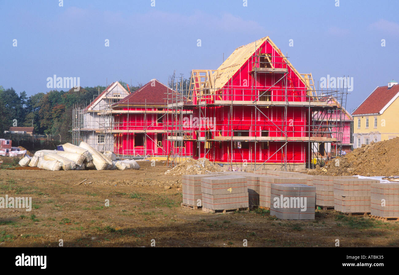 Building site with red cladding and scaffolding as new houses are built ...