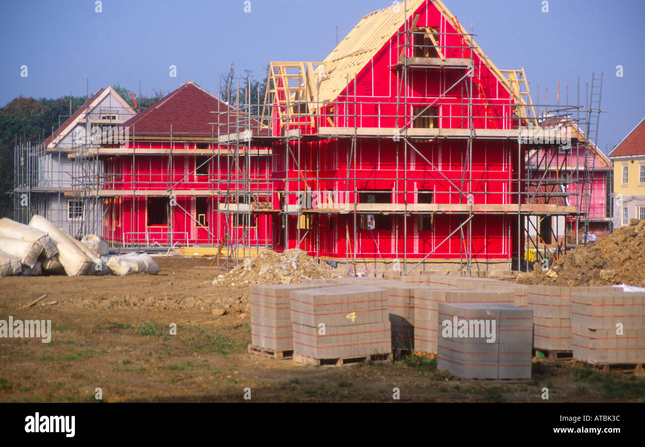 Building site with red cladding and scaffolding as new houses are built ...