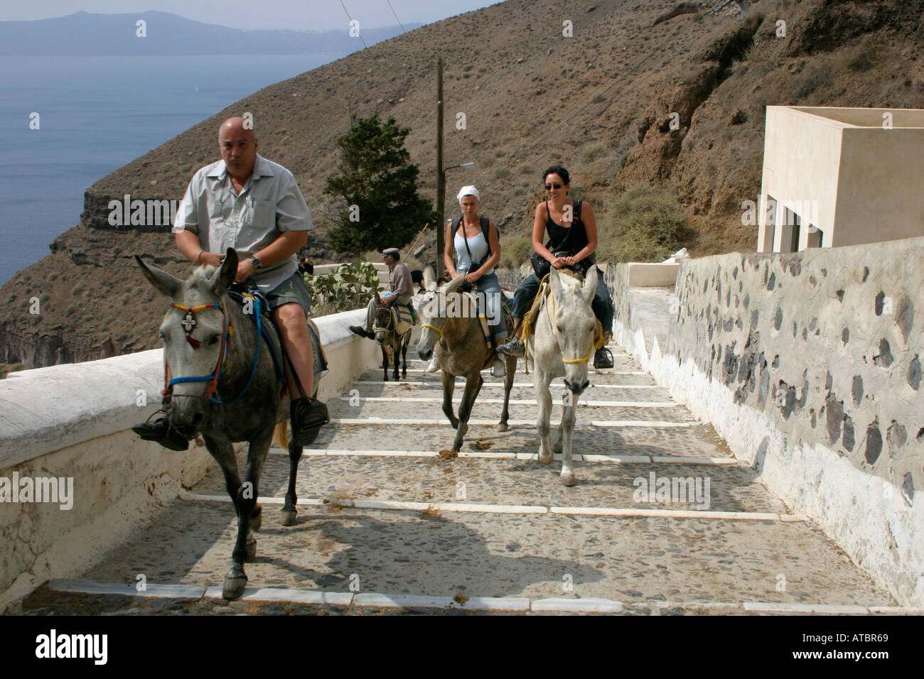 Visitors riding donkeys up the harbour steps in Fira Santorini Stock ...