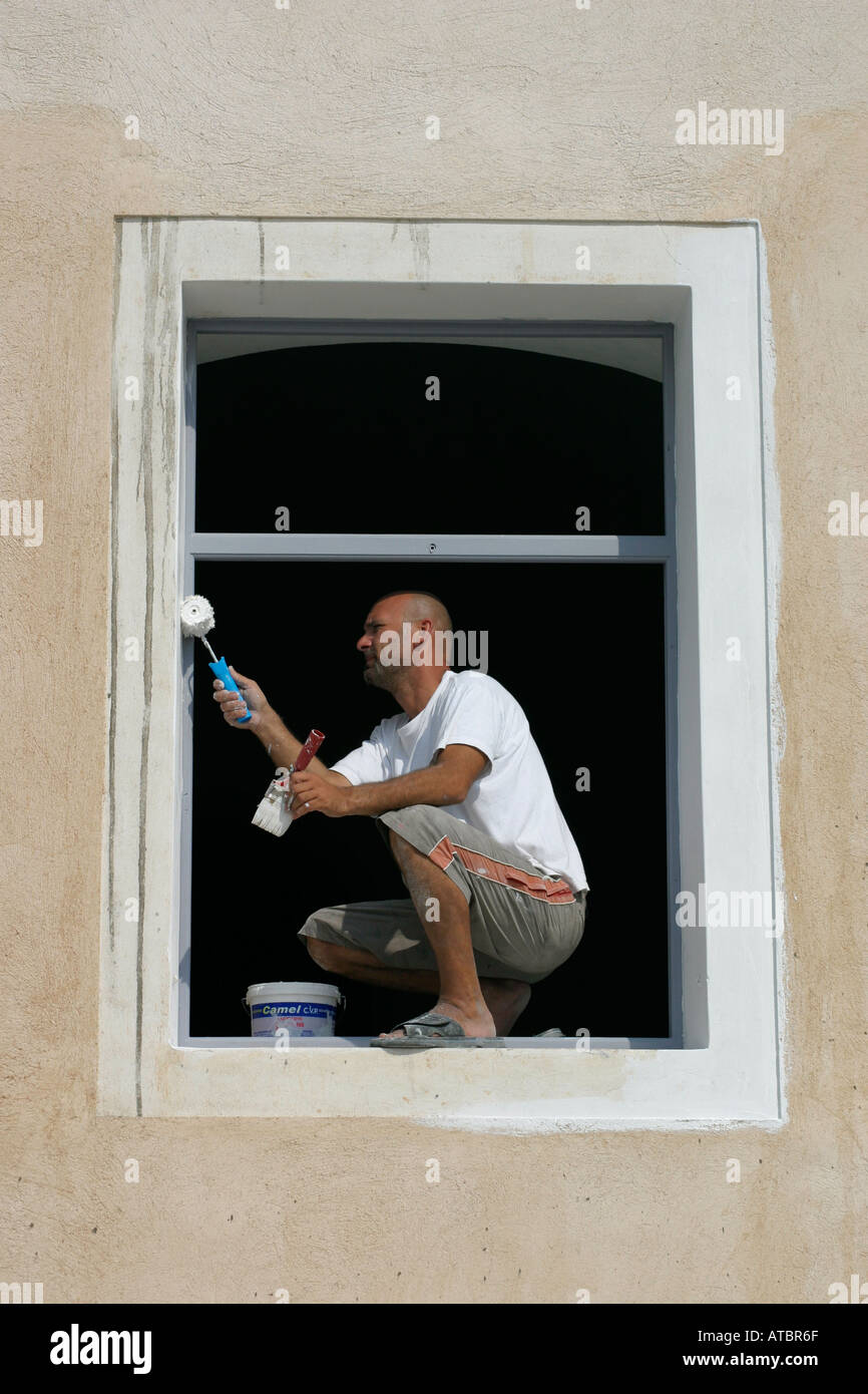Greek man painting a window frame in Fira Santorini Stock Photo - Alamy