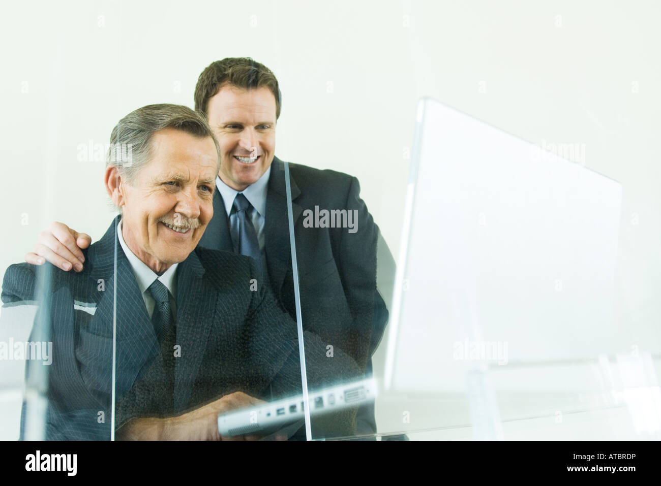 Businessman looking over colleague's shoulder at laptop computer, both ...