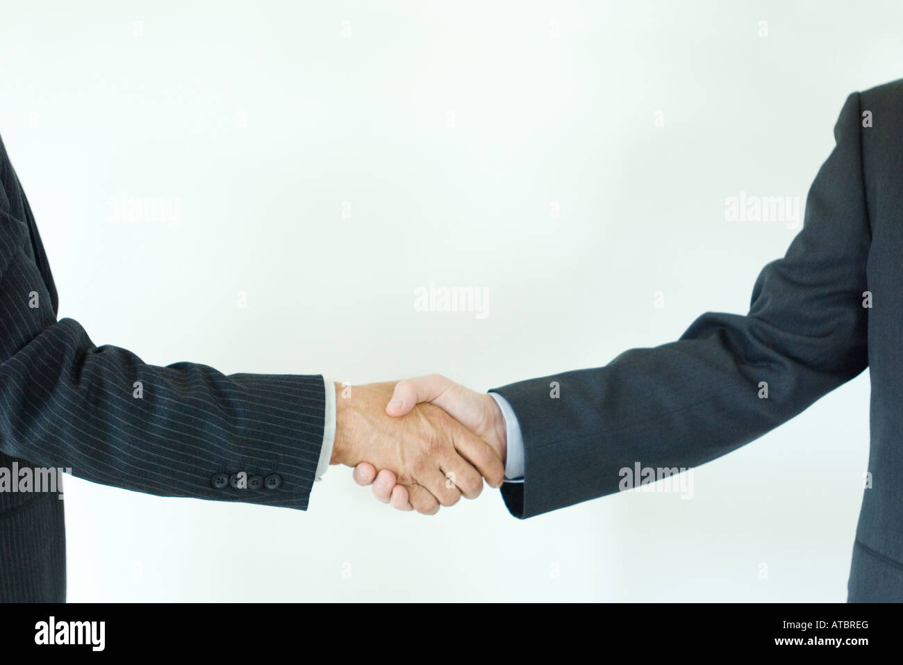 Two businessmen shaking hands, cropped side view Stock Photo - Alamy