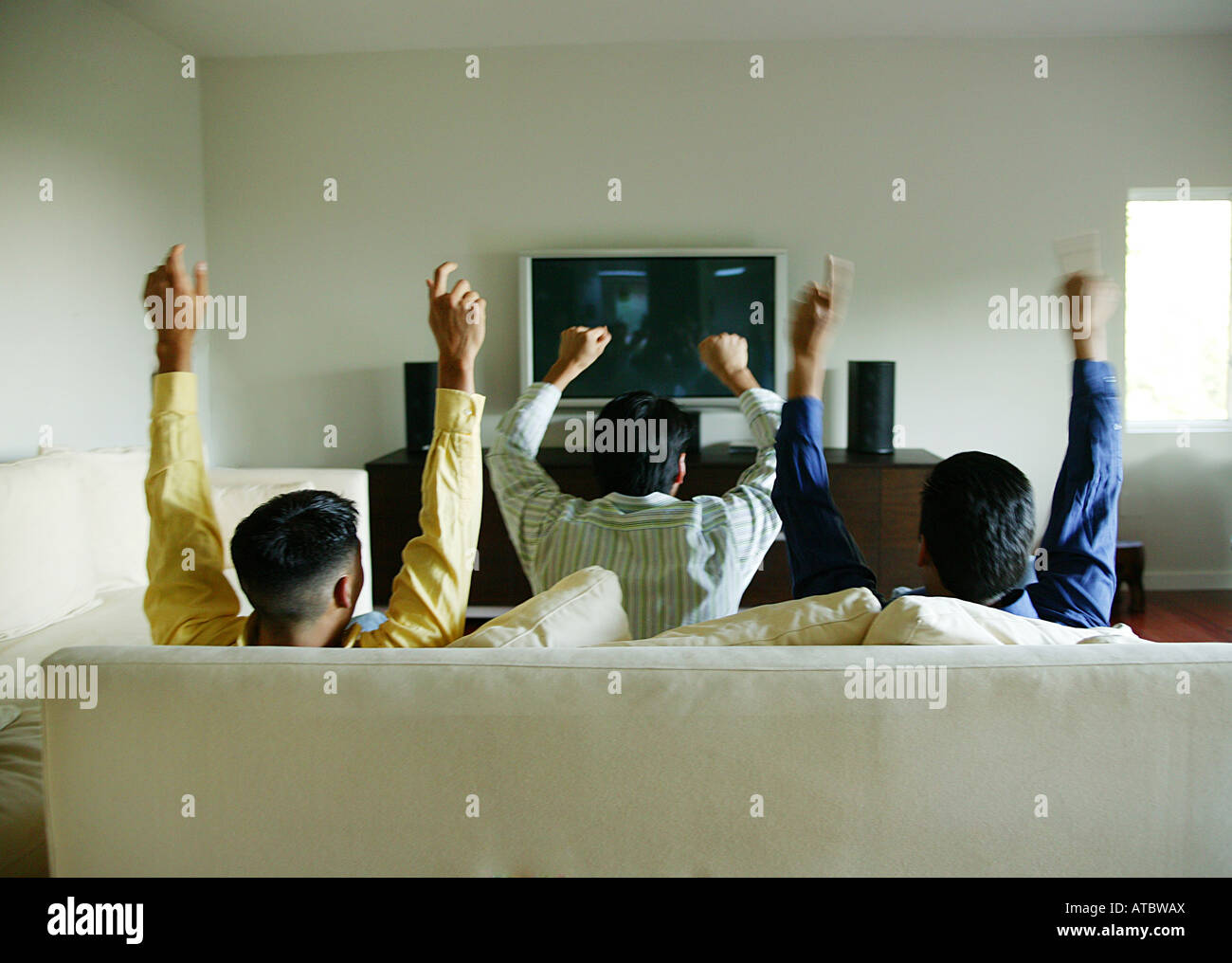 3 Men Cheering Watching Flat Screen TV Stock Photo - Alamy