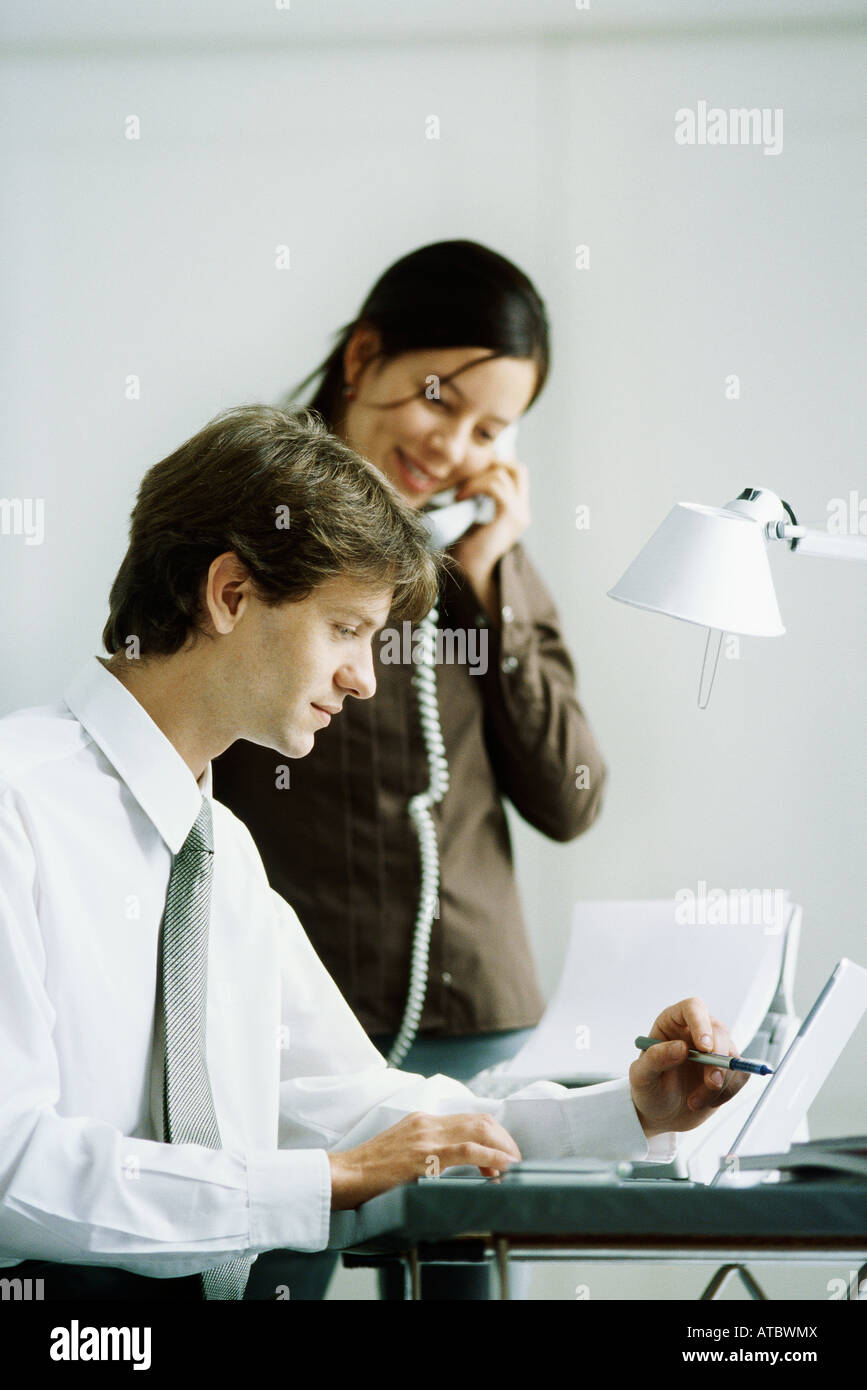 Male and female colleagues looking at laptop computer together, man ...