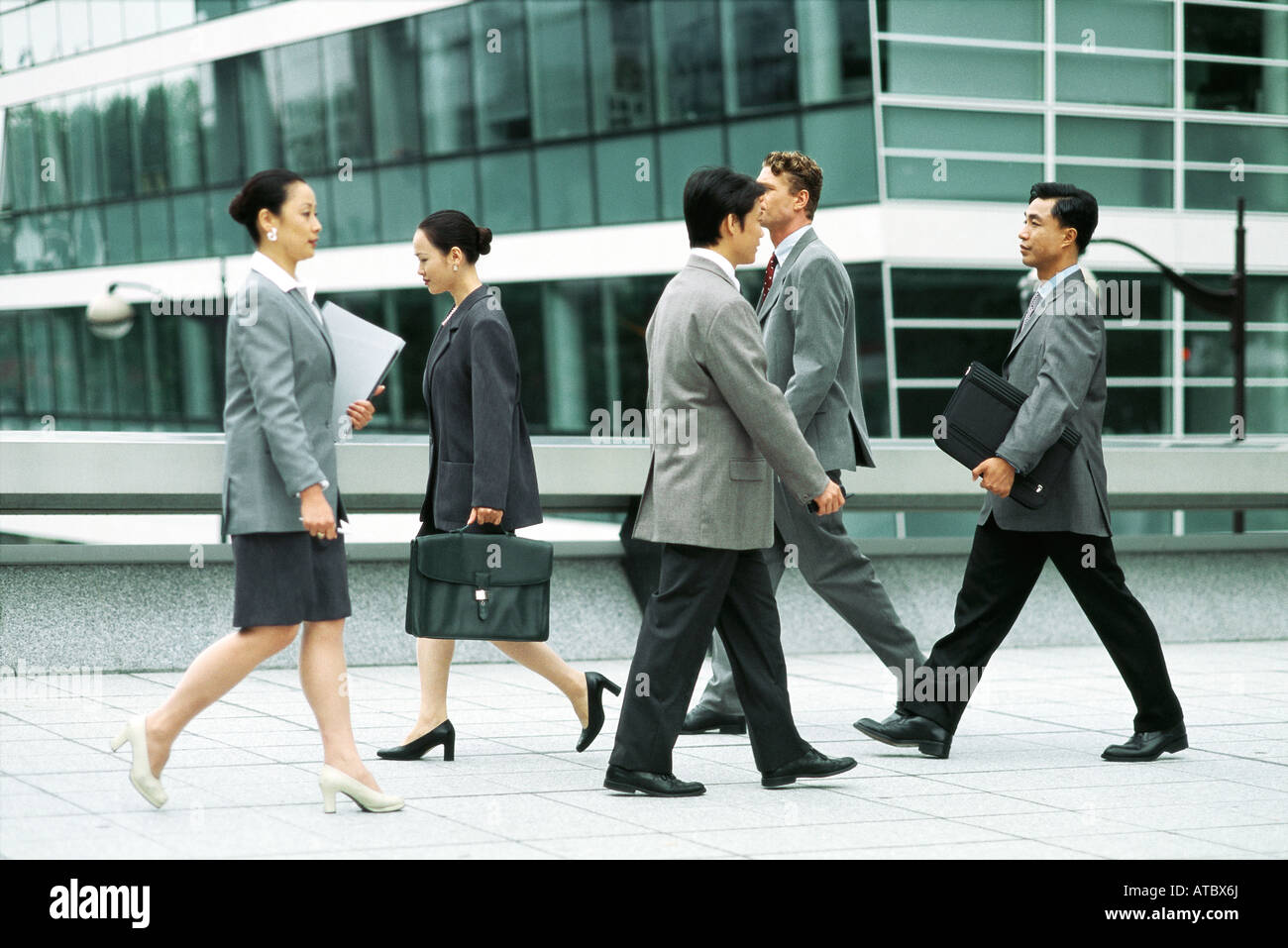 Male and female professionals walking on busy sidewalk, side view Stock ...