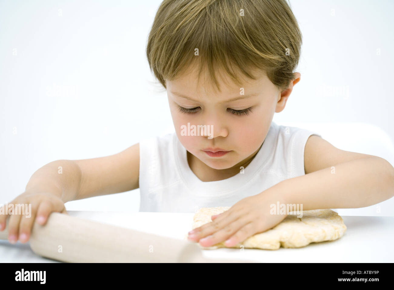 Toddler boy rolling out dough with rolling pin, close-up Stock Photo ...