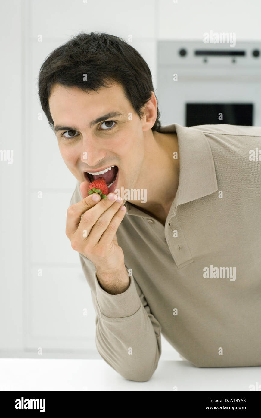 Man eating strawberry, looking at camera, close-up Stock Photo - Alamy