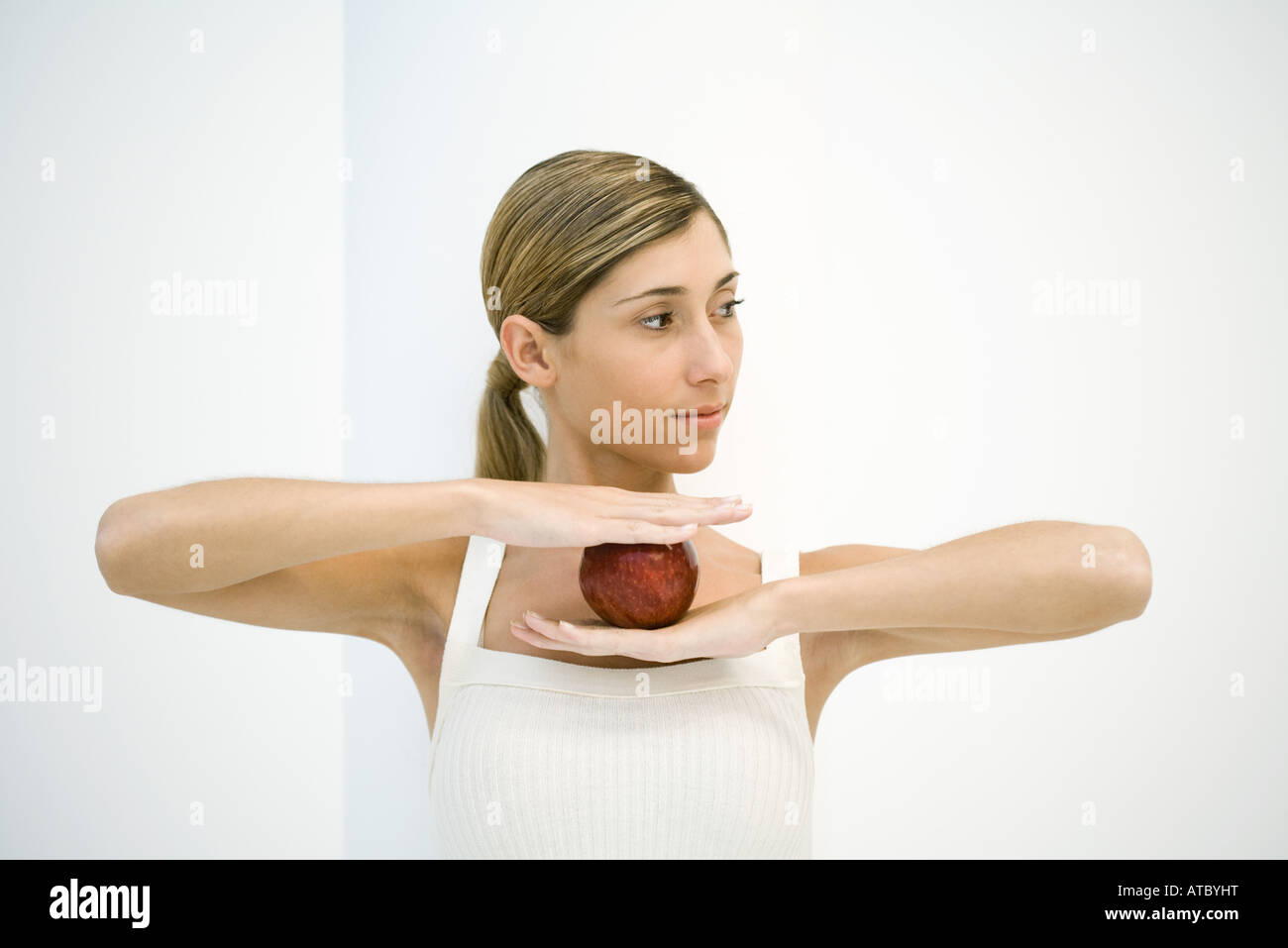 Young woman holding apple, arms raised, looking away Stock Photo - Alamy