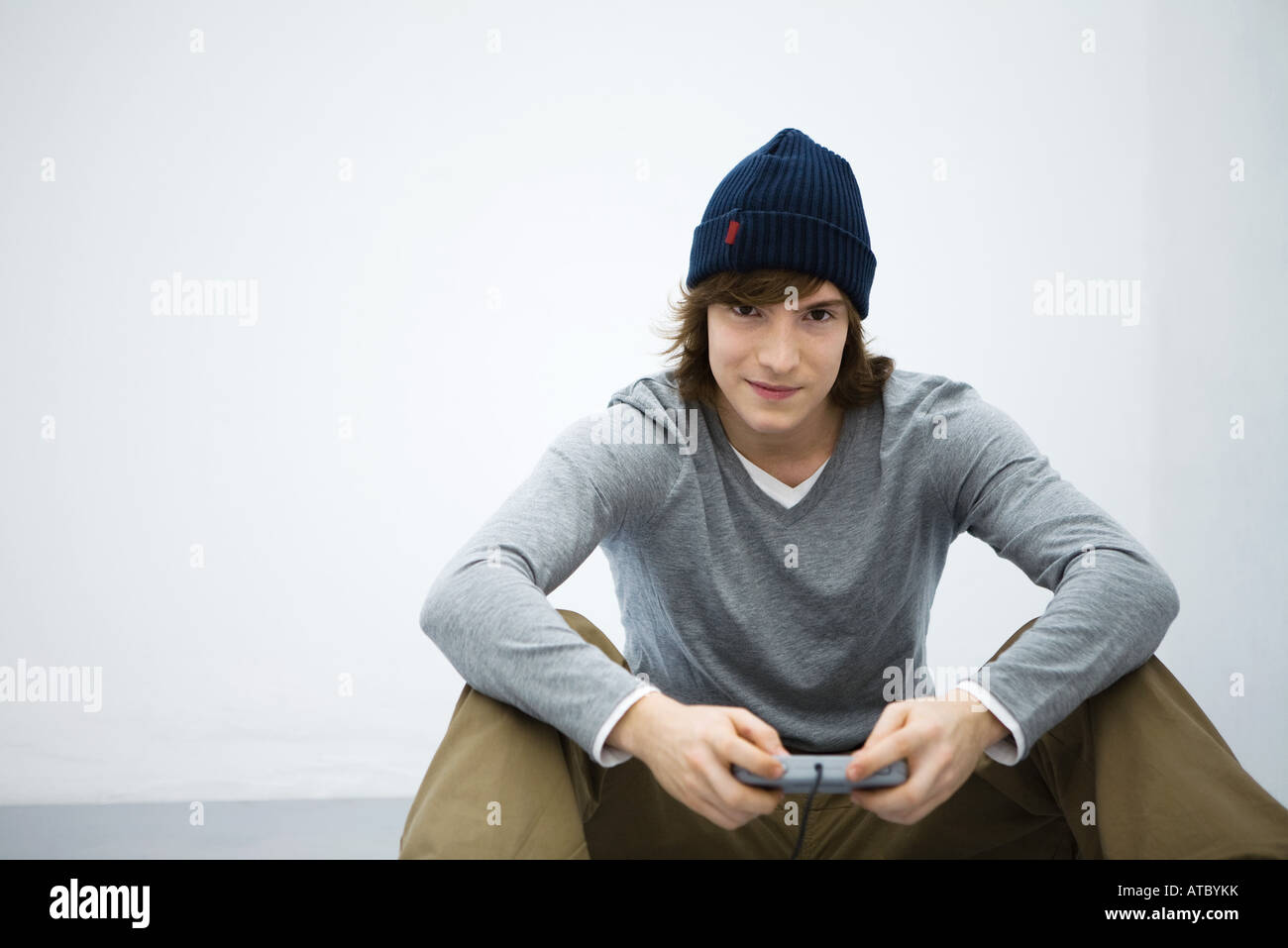 Young man sitting on the ground, holding video game controller, smiling ...
