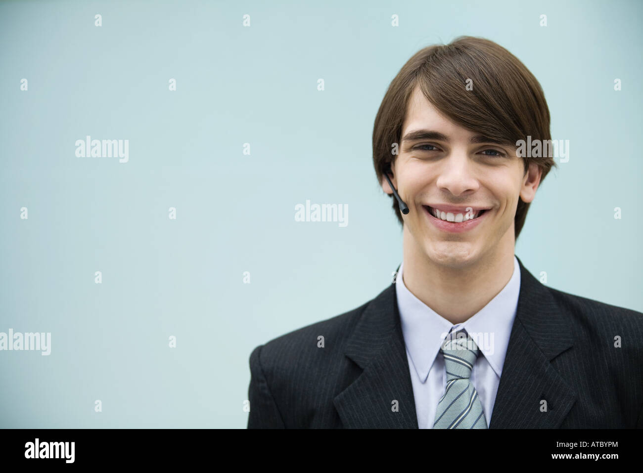 Young man in suit using headset, smiling at camera, portrait Stock ...