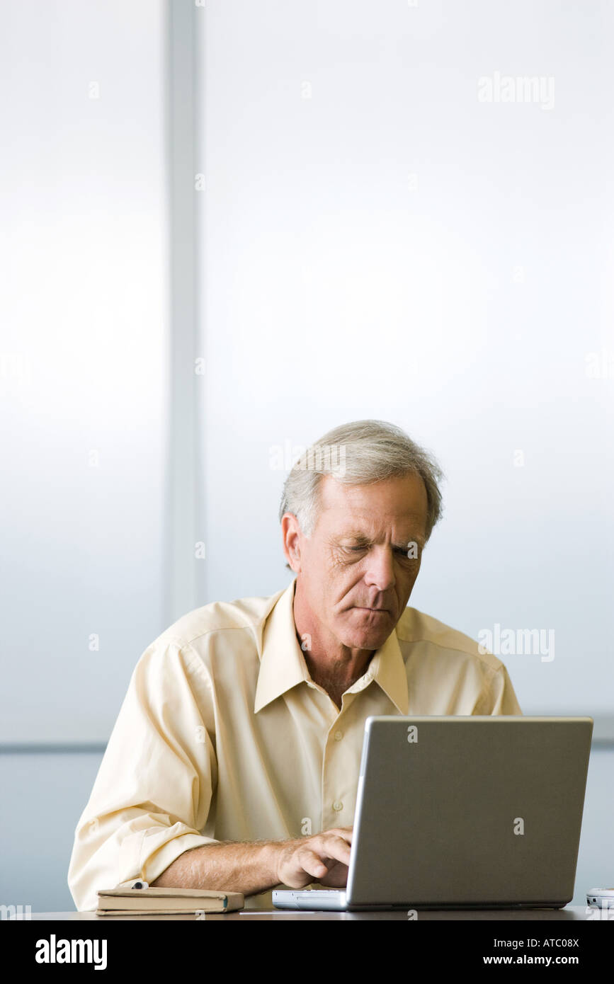 Man sitting, using laptop computer, looking down Stock Photo - Alamy