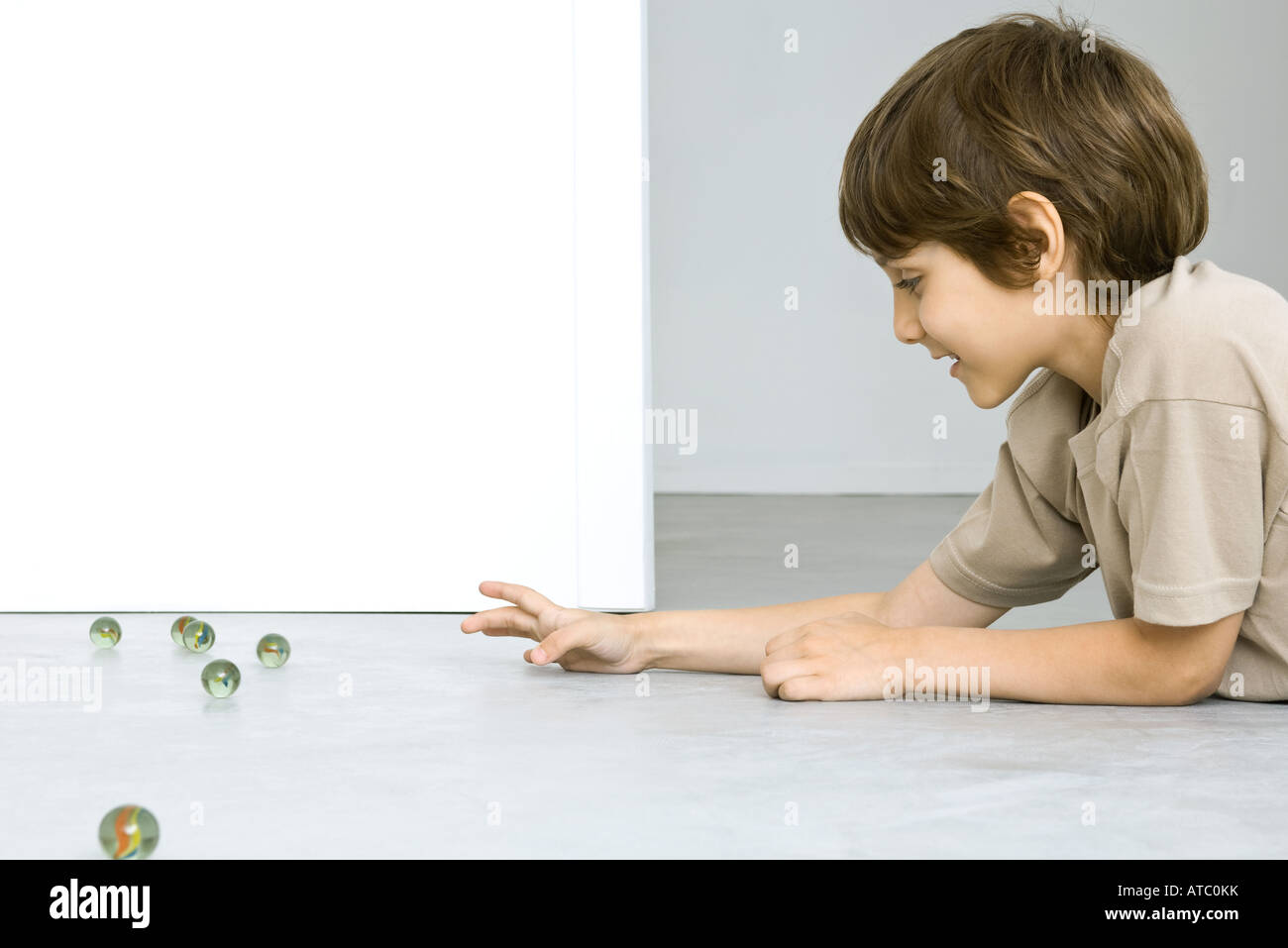 Little boy lying on the ground playing with marbles, side view Stock ...